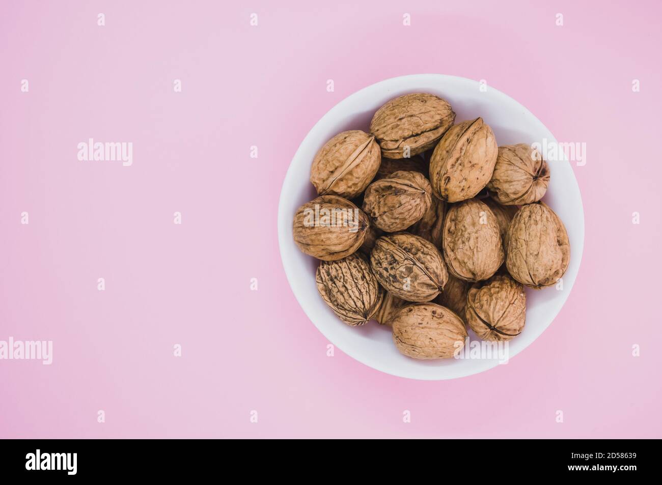 Top view of walnuts on a white bowl isolated on a pink background Stock ...