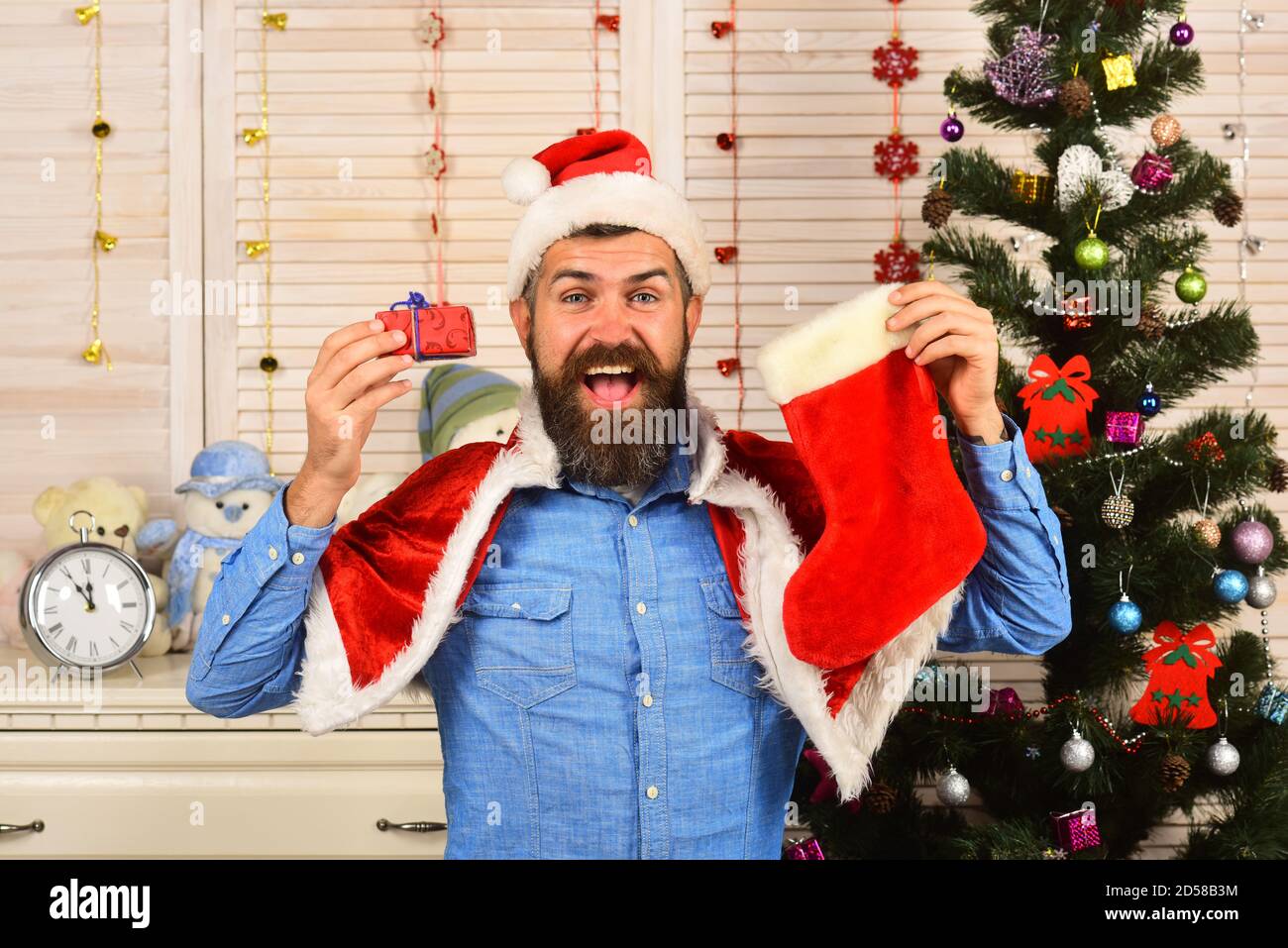 Celebration and gift concept. Guy in hat and red and white cape holds ...