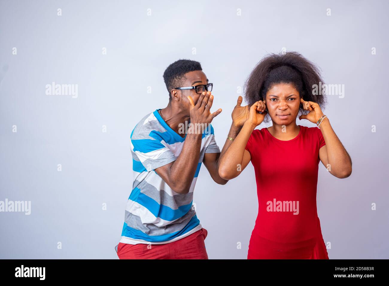 young african man yelling at a lady who covers her ears with her finger ...