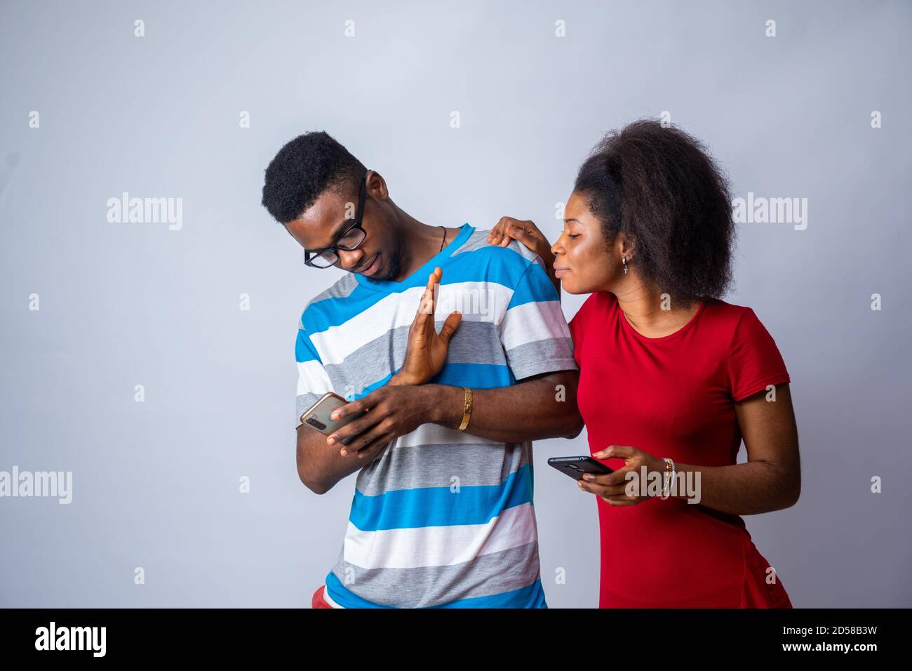 african lady tries to spy at a man's phone who is shielding her from ...