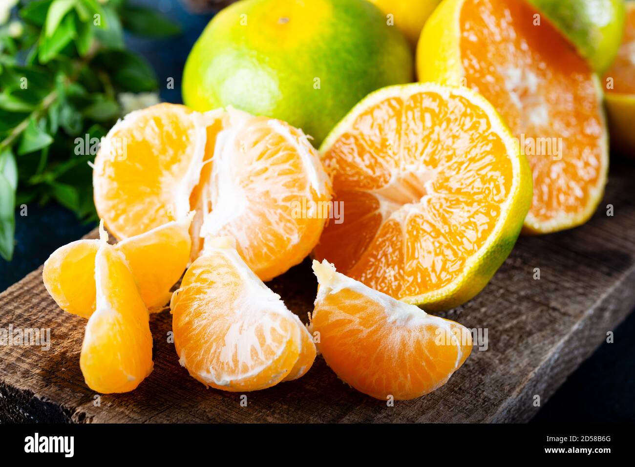 Ripe Mandarin fruit peeled open and place on old rustic look timber ...