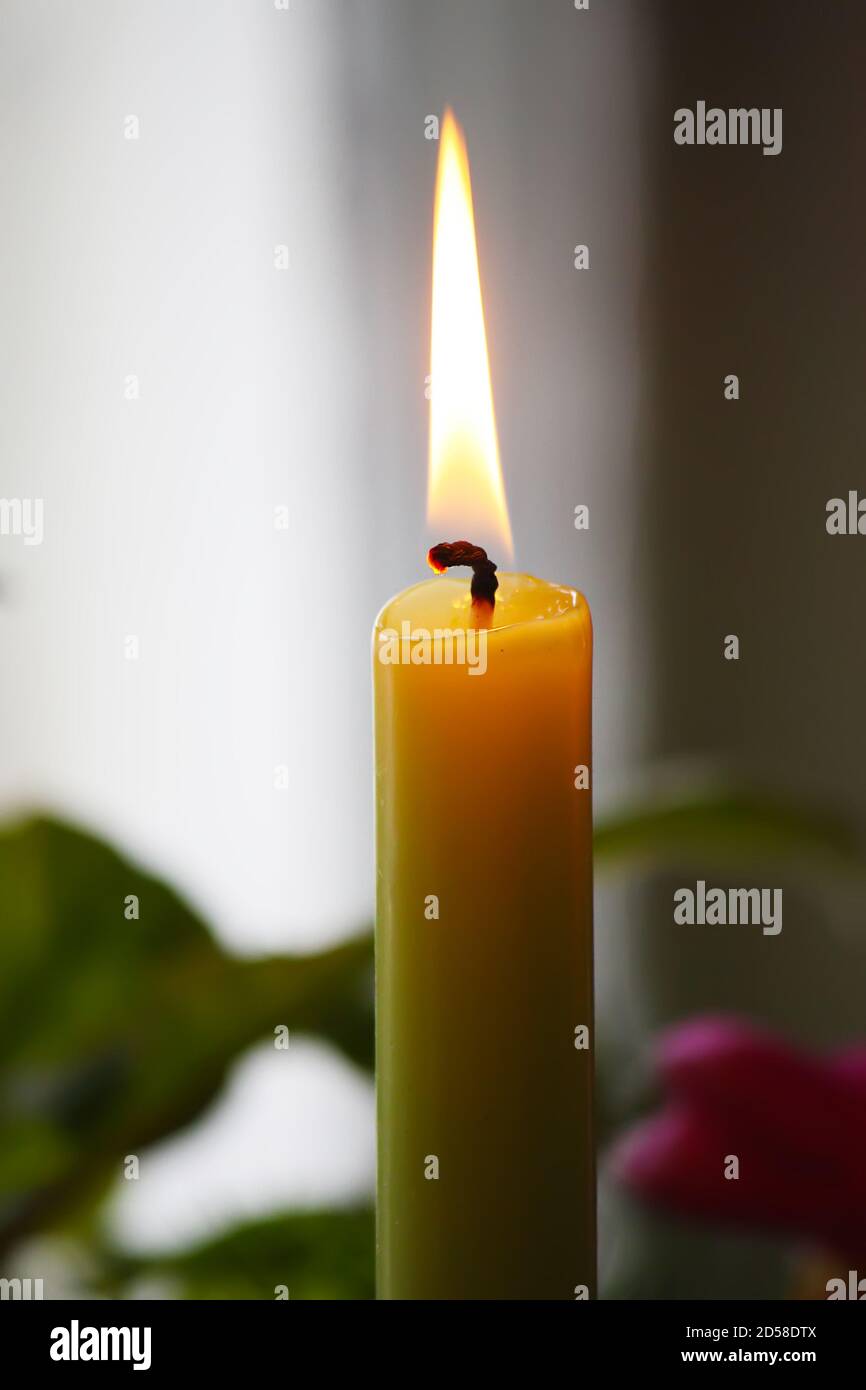 Shot of yellow burning candle on dark background Stock Photo - Alamy