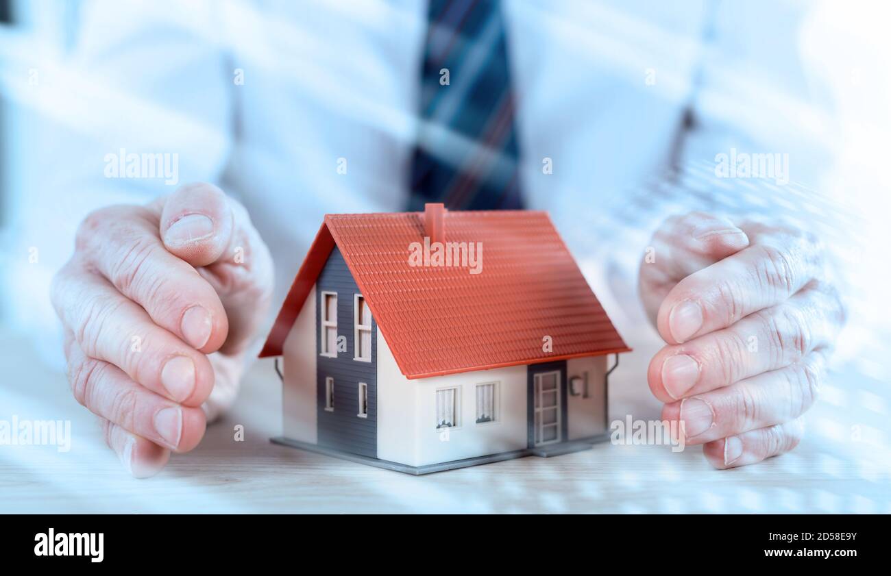 Insurance agent protecting house with his hands; multiple exposure ...