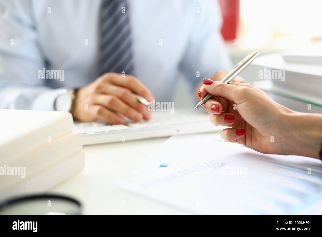 Female hand holds ballpoint pen over documents closeup in front of man ...