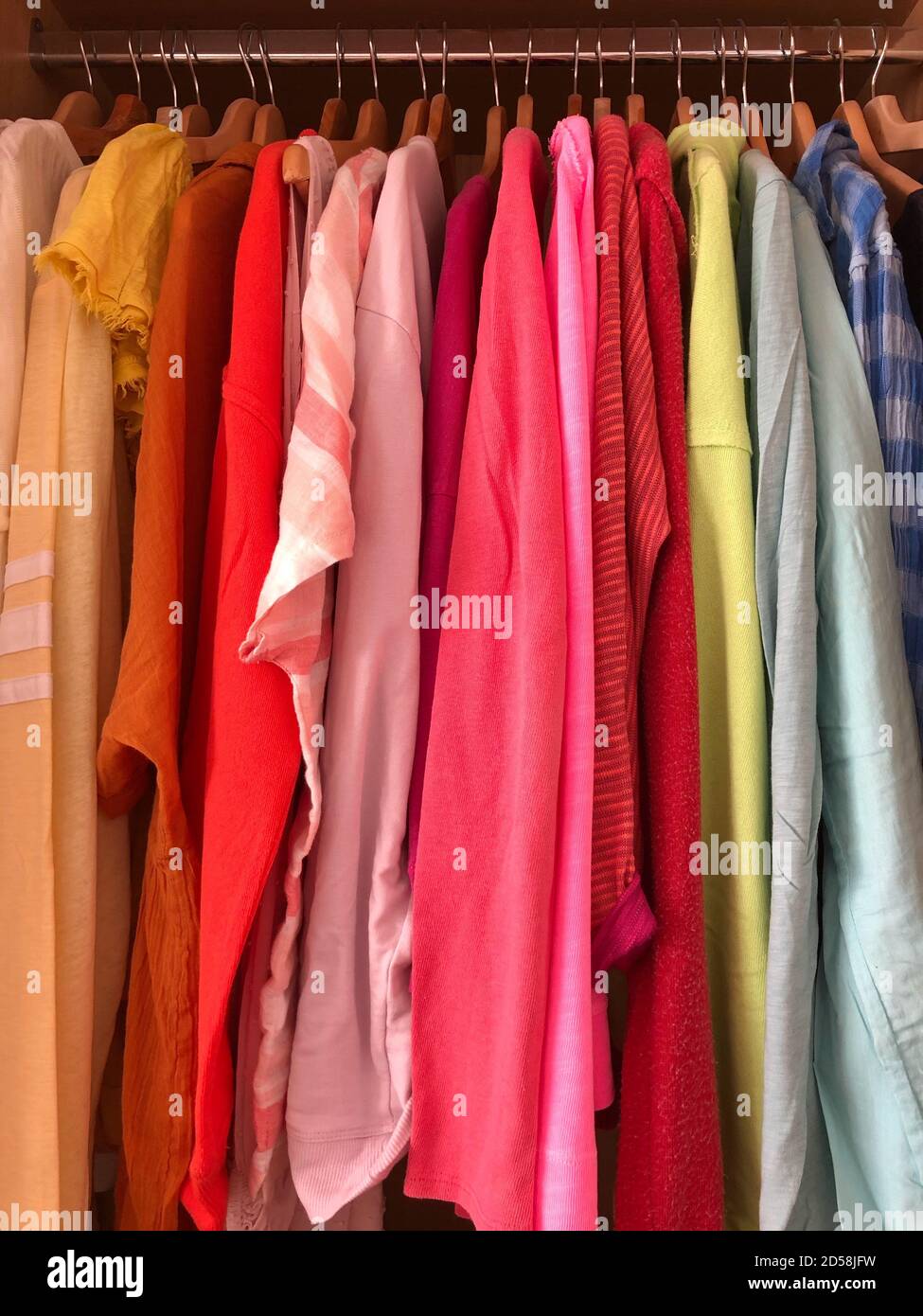 Rainbow coloured tops hanging in a wardrobe Stock Photo - Alamy
