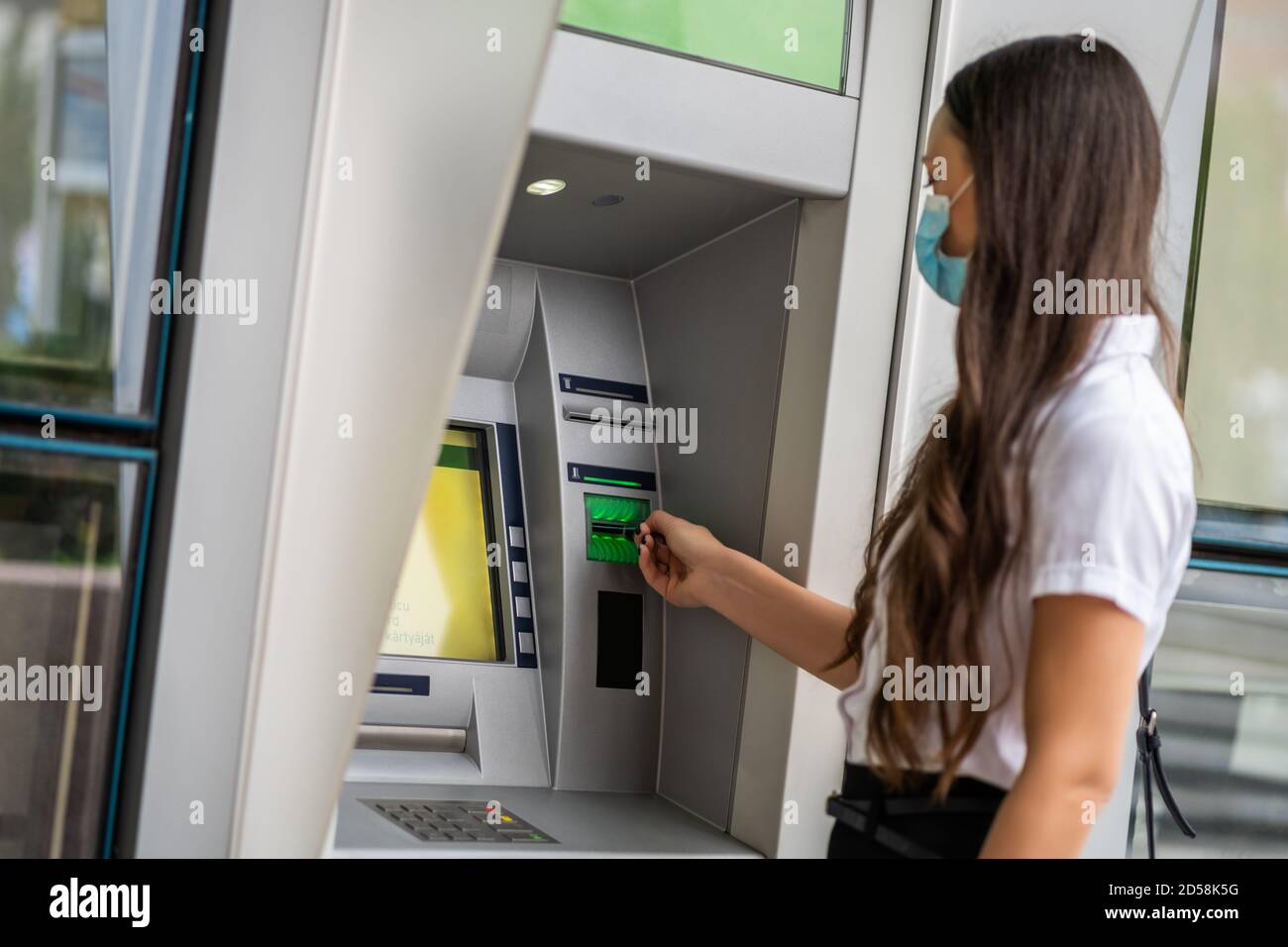 Businesswoman with protective mask is using ATM machine to withdraw ...