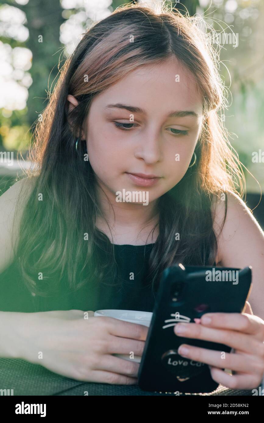 Teenage girl using her cell phone, while having a cup of tea. Teenage ...