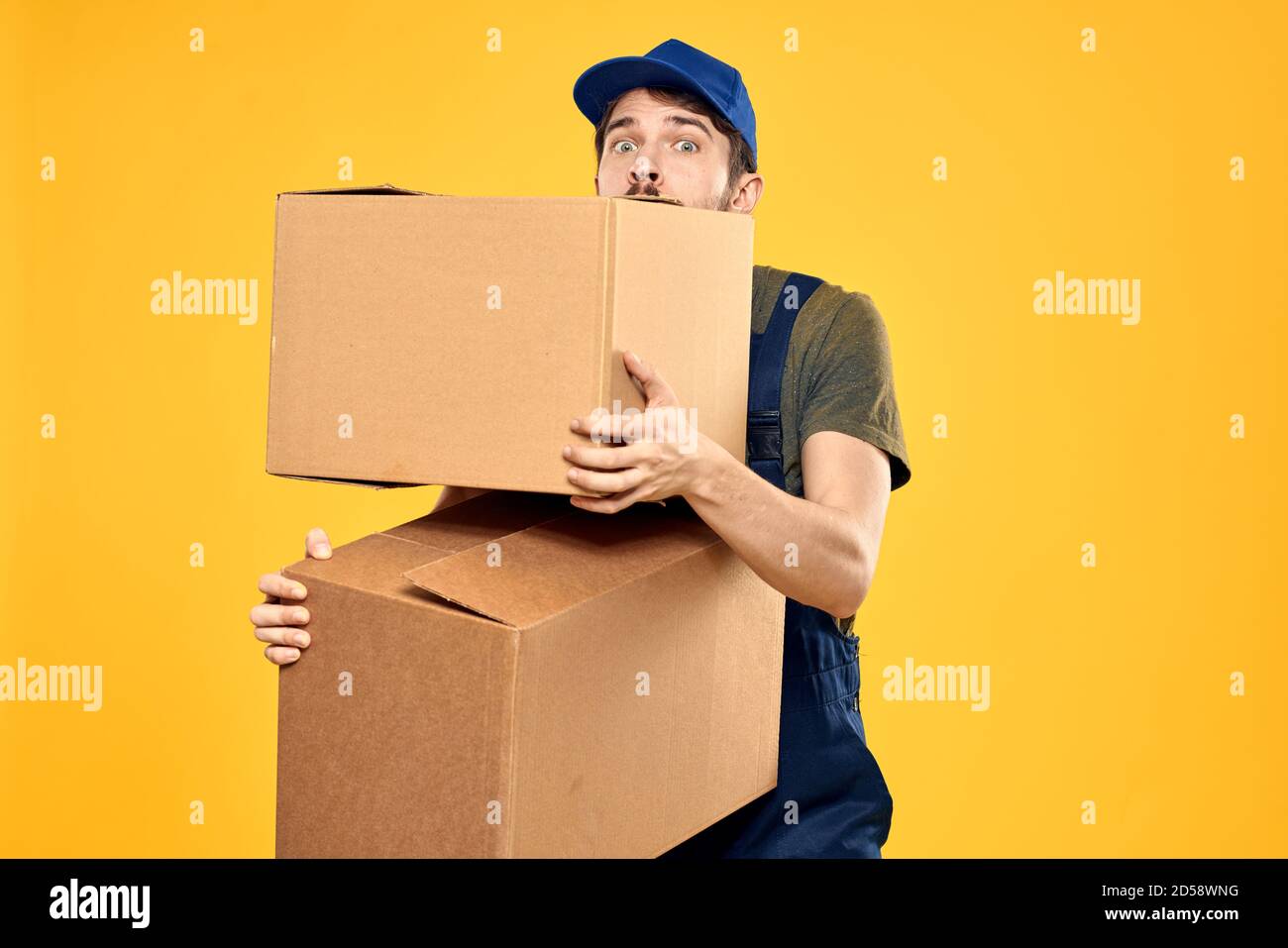 A man in a working form a box with loading tools yellow background ...