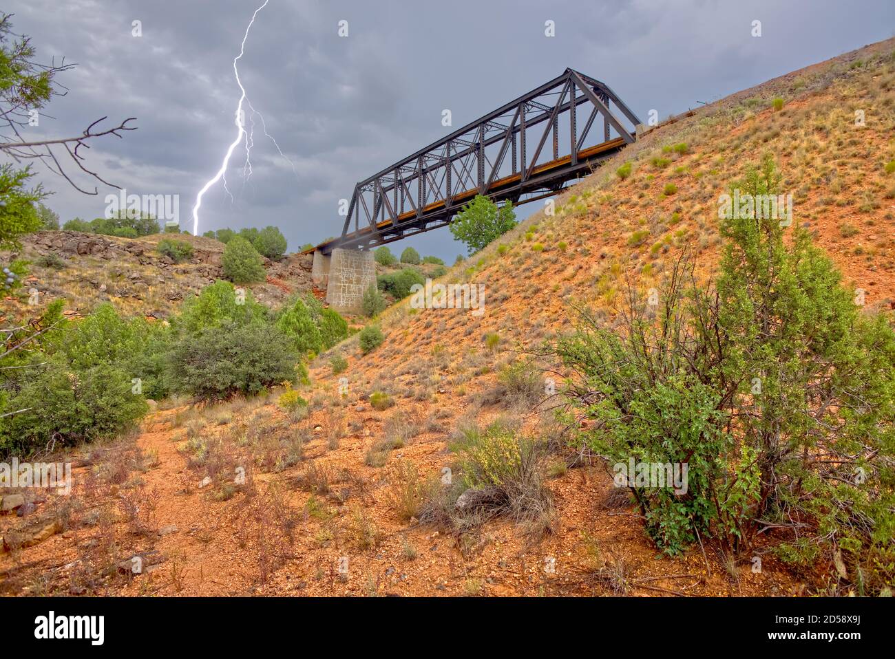 Lightning from a monsoon storm striking near an old railroad trestle ...