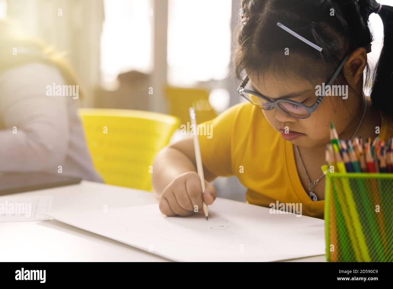 Asian girl with Down's syndrome drawing picture in art class. Concept ...
