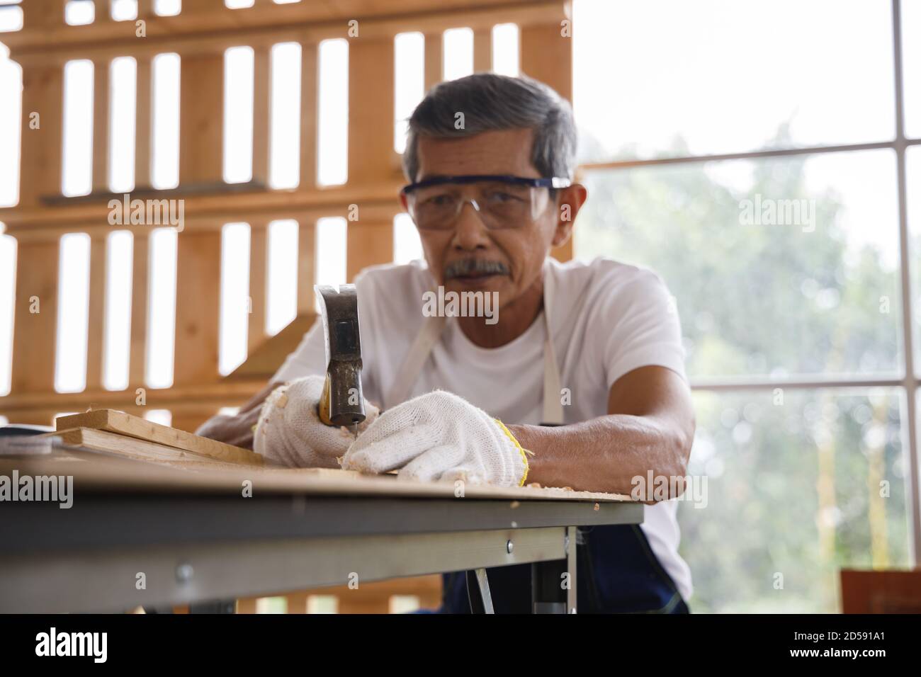Asian senior man nail wooden board in carpentry workshop. Concept ...