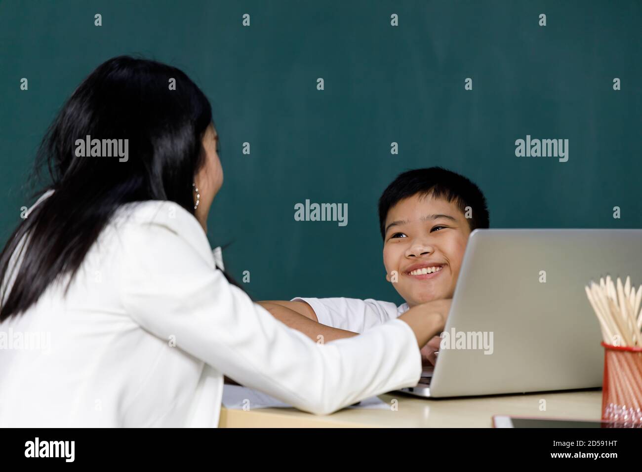 Asian boy study by using laptop computer with his teacher in classroom ...