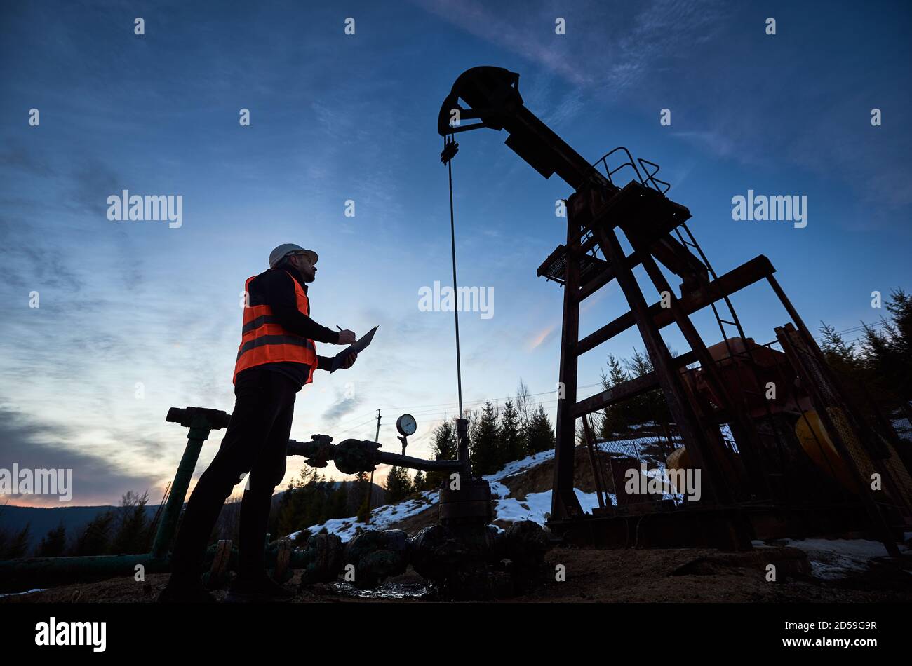 Low angle side view snapshot of petroleum engineer wearing orange vest ...