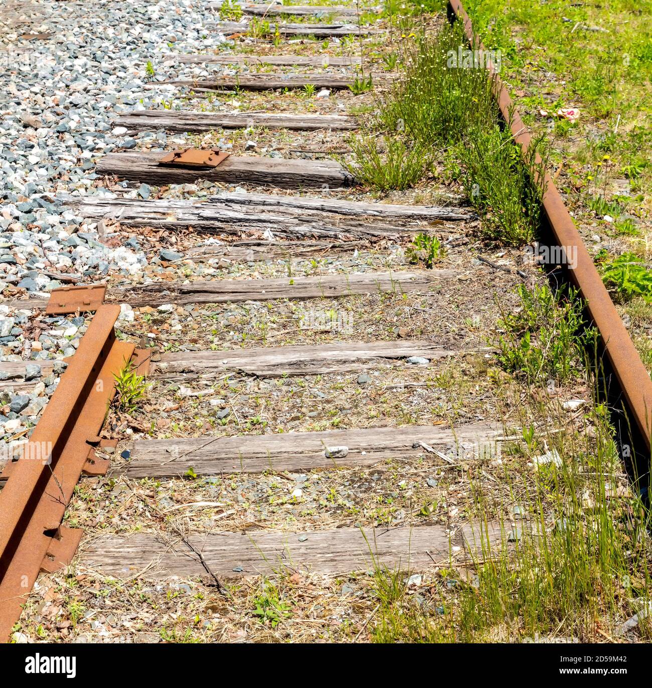 A rusty, abandoned railway track. Part of the right rail is missing ...