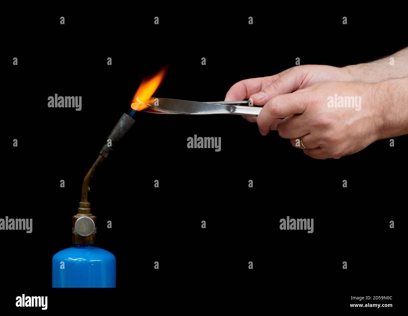 Two hands holding table knives in a torch flame in preparation for ...