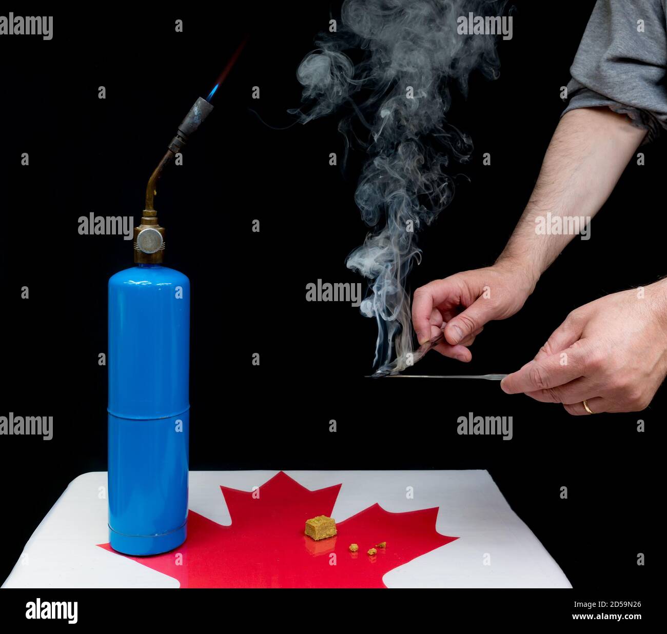 Two hands holding table knives for doing "hot knives" of hashish ...