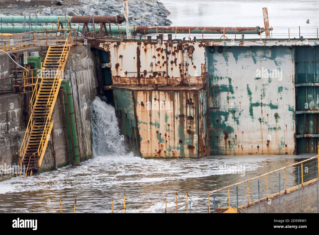An old dry dock that is no longer in use. A torrent of water flows into ...