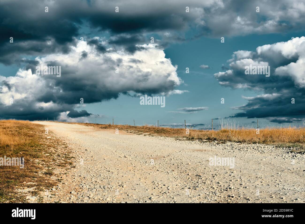 Empty pebble road to nowhere disappearing on the horizon with blue sky ...