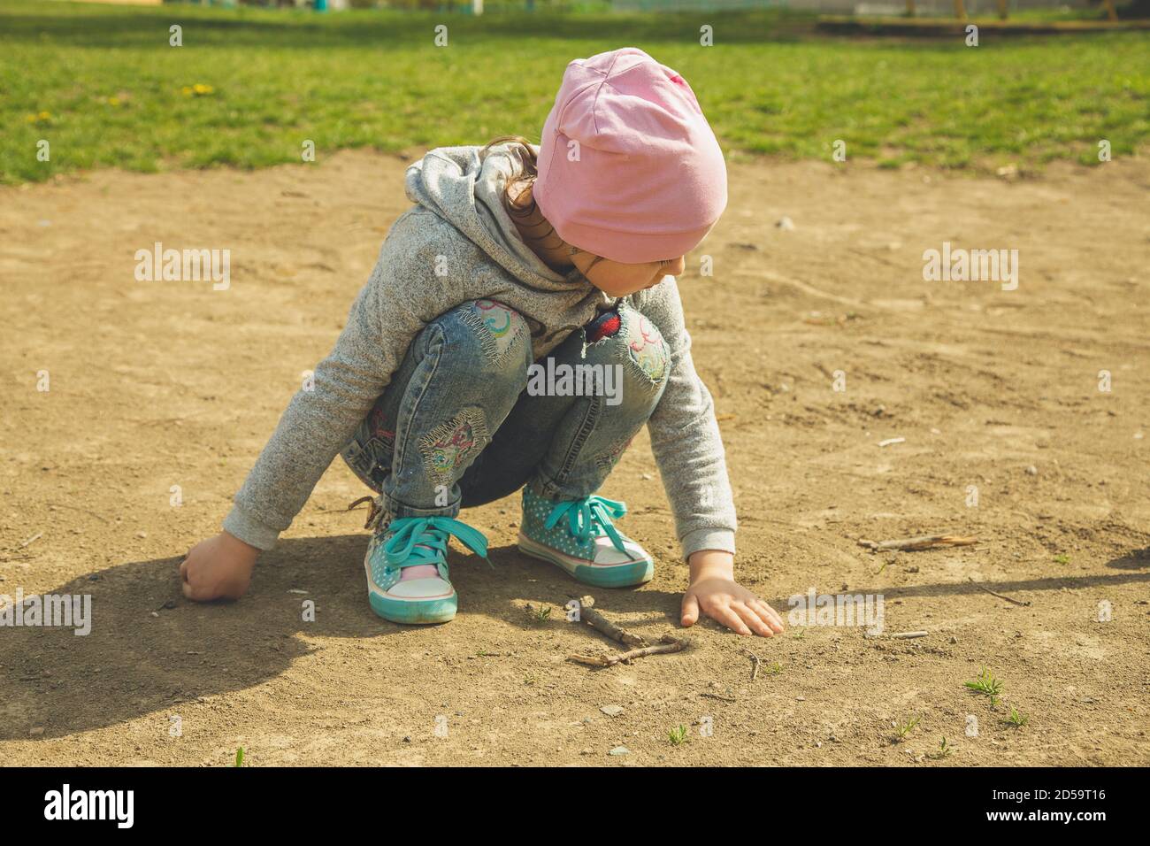 Poor, sad little child girl sitting on the ground and playing outdoor ...