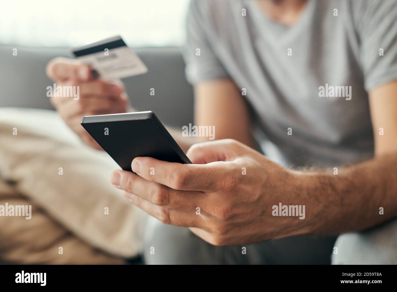 Man shopping online with mobile phone and credit card, adult male buying on internet from his ...