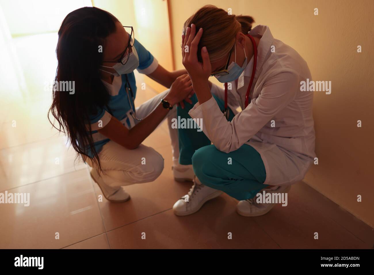 Nurse calms crying doctor wearing medical protective mask in bright ...