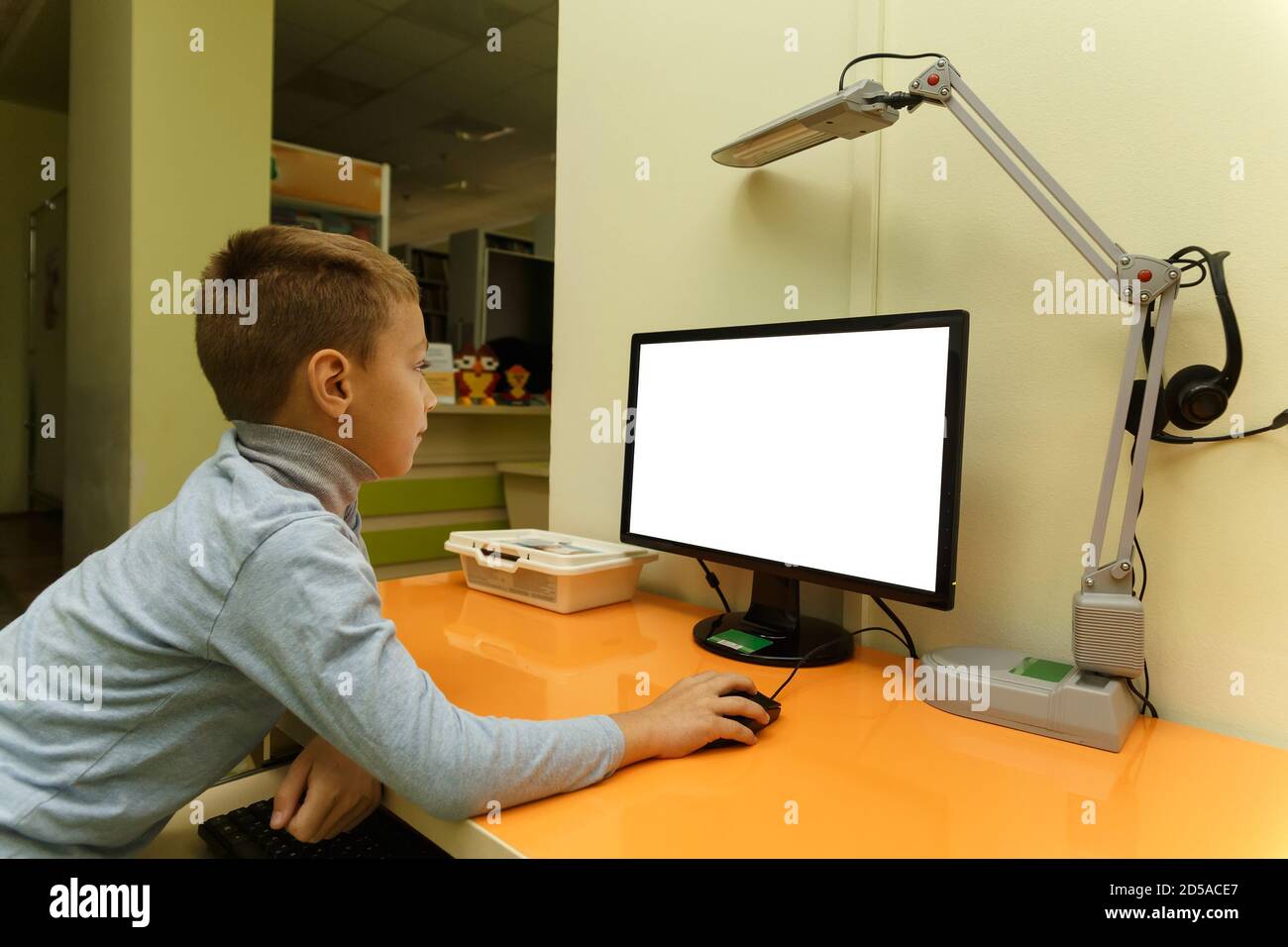 Caucasian boy with his friends learning to use a computer at the school ...