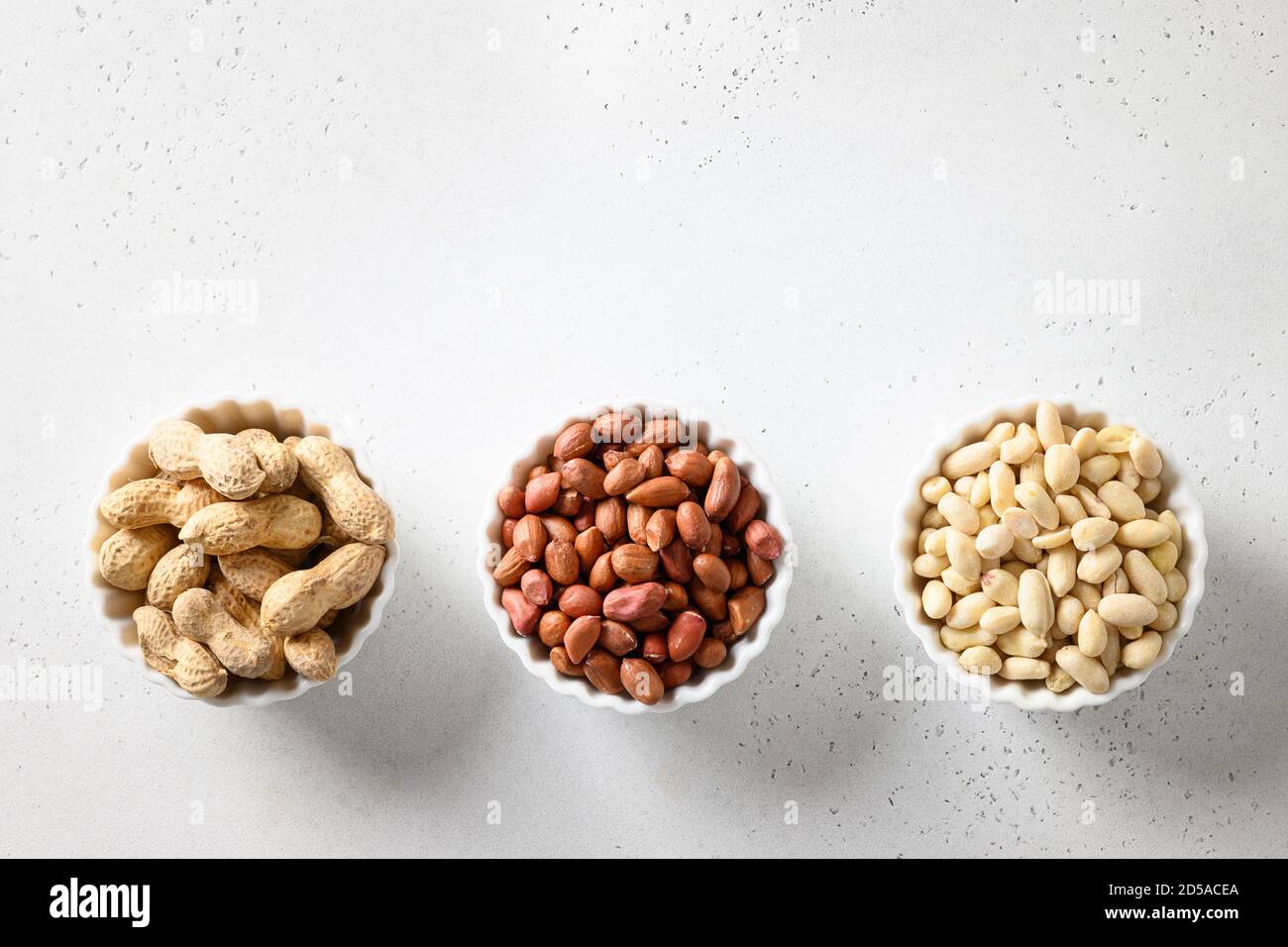 Peanut in three types with peel, roasted and peeled in bowls on white ...
