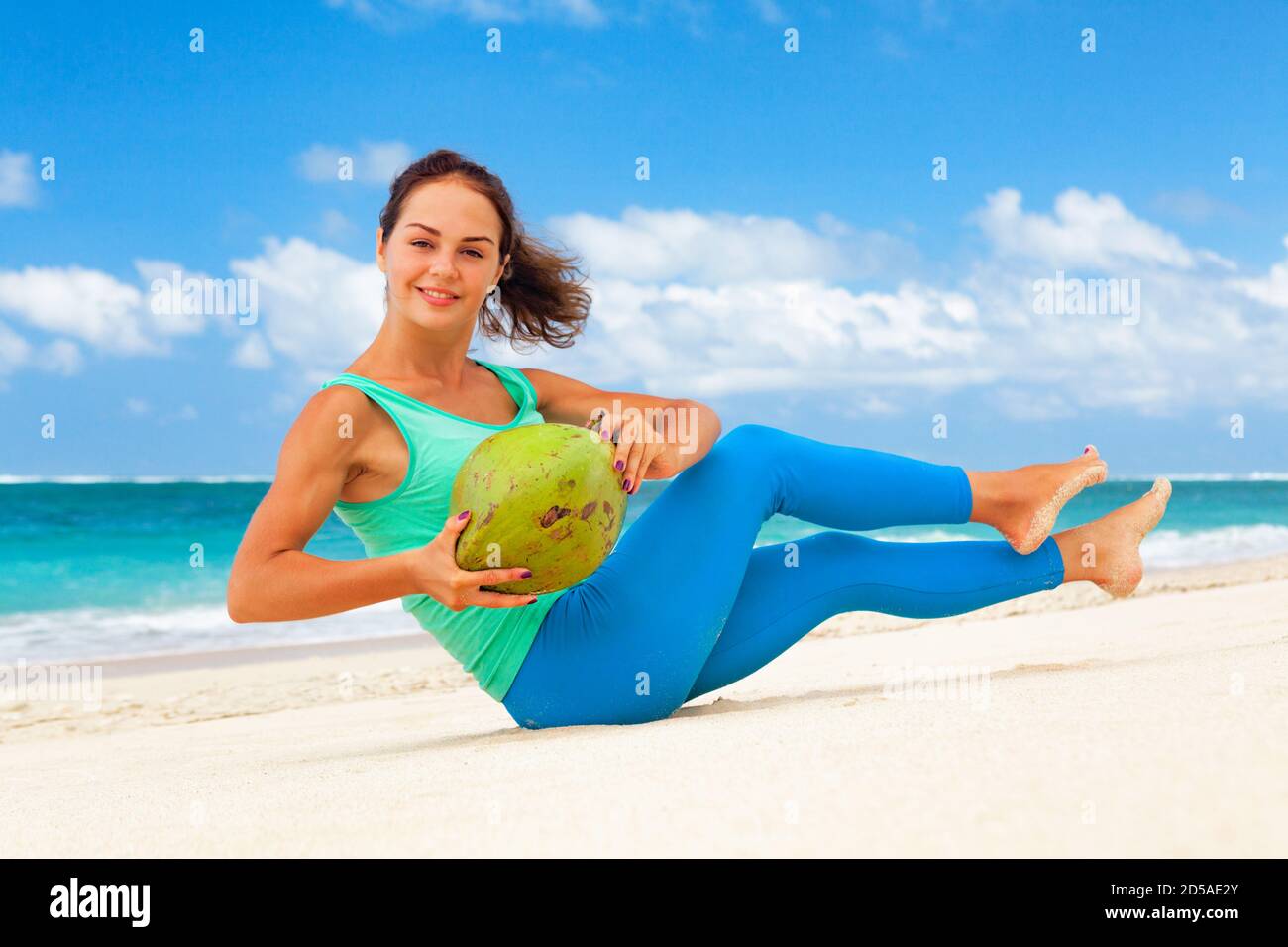 Young woman doing abdominal exercise on sea beach to keep fit and ...