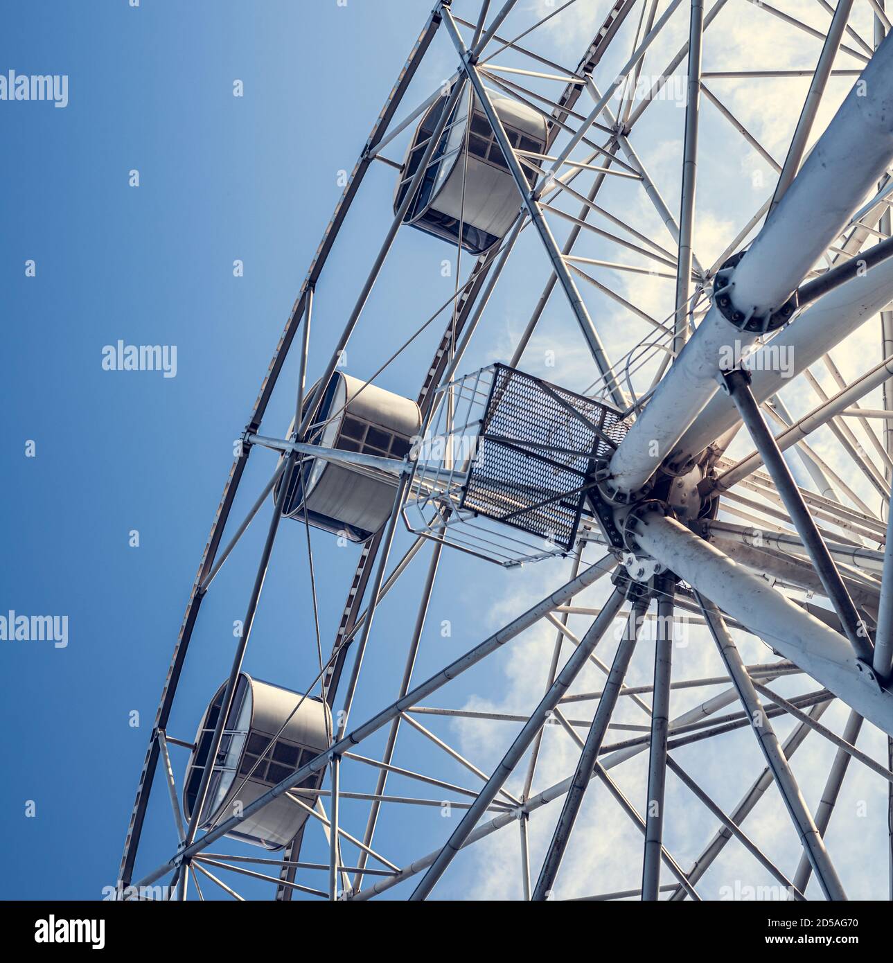 Gray or white metal ferris wheel with closed passenger cabins close-up ...