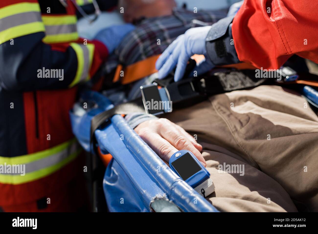 Cropped view of patient with heart rate monitor lying on stretcher near ...