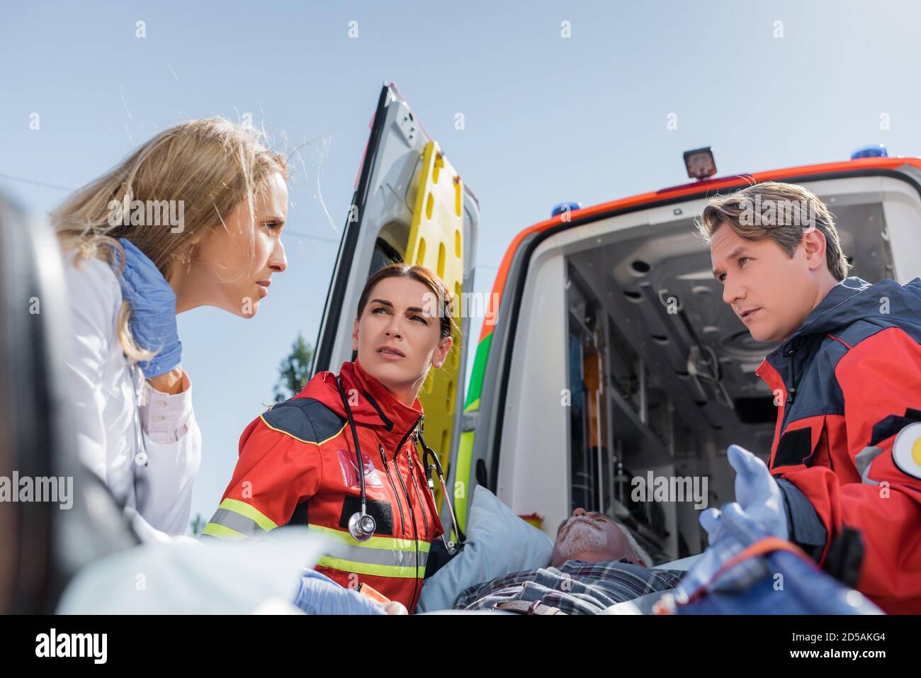 Selective focus of doctor looking at paramedic near patient on ...