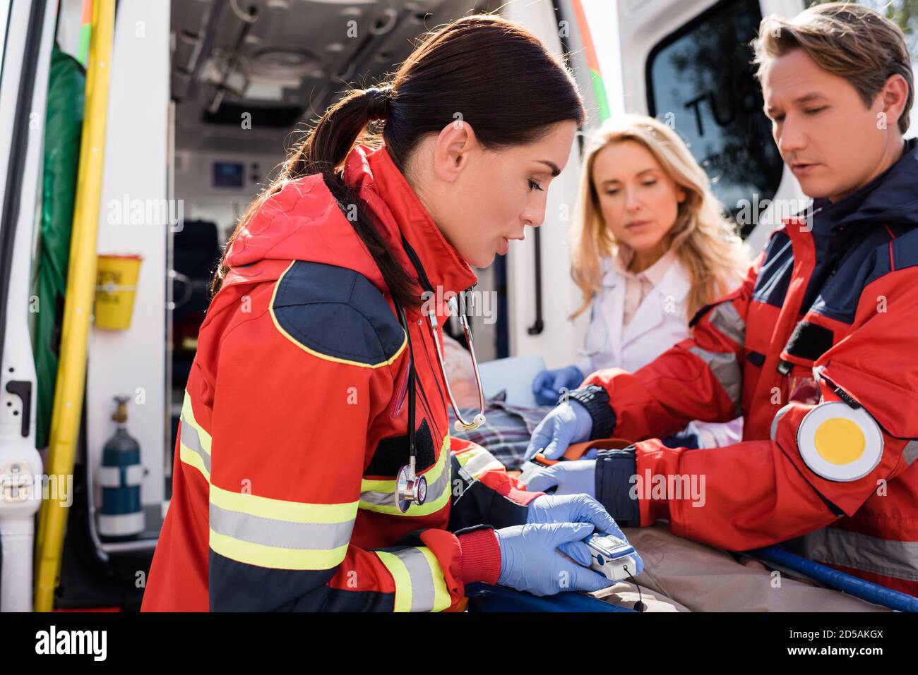 Selective focus of paramedic in latex gloves holding heart rate monitor ...