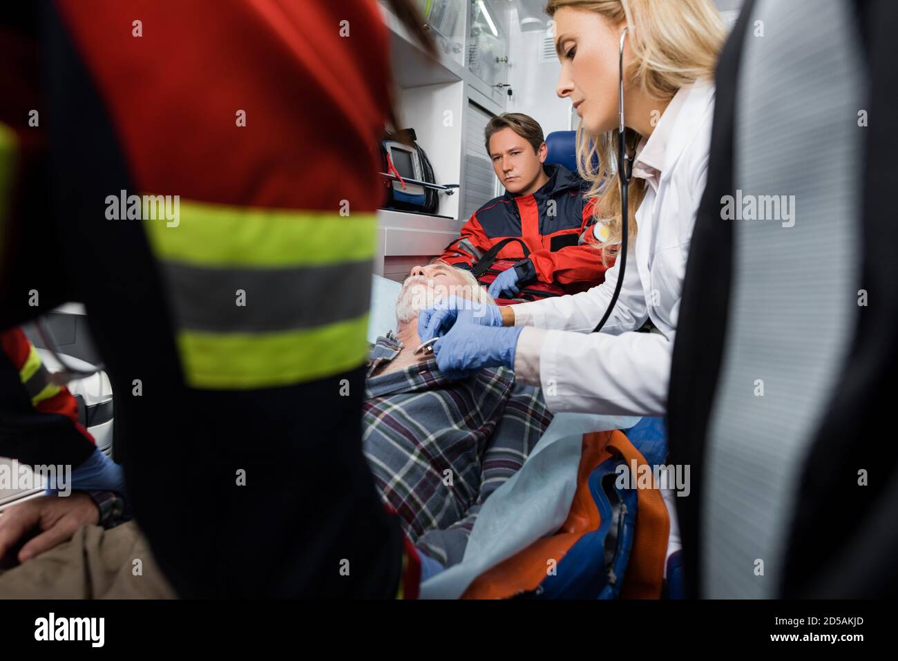 Selective focus of paramedics standing near doctor examining patient ...
