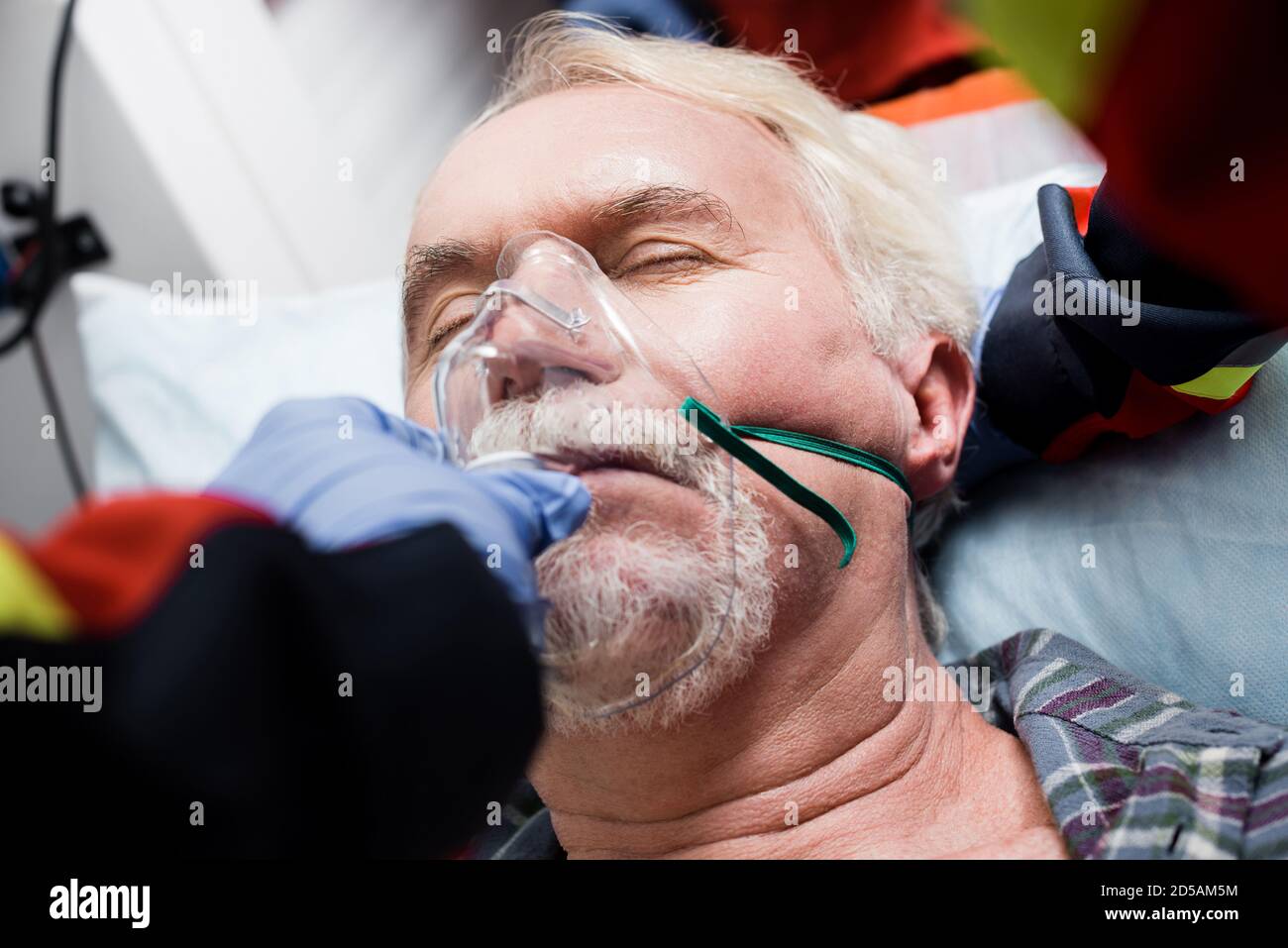 Selective focus of paramedic wearing oxygen mask on ill patient during ...