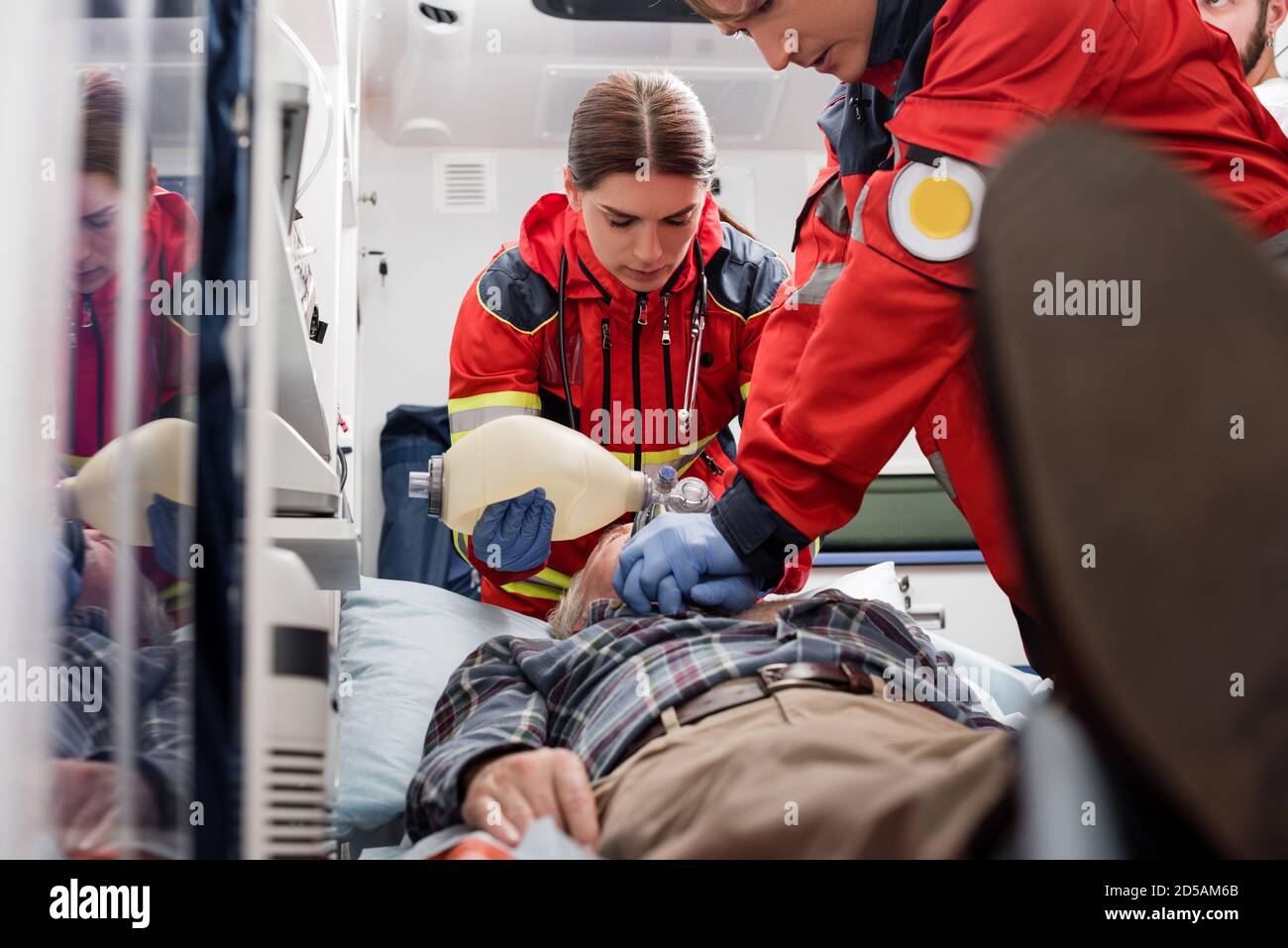 Selective focus of paramedics in uniform doing cardiopulmonary resuscitation to man during first ...