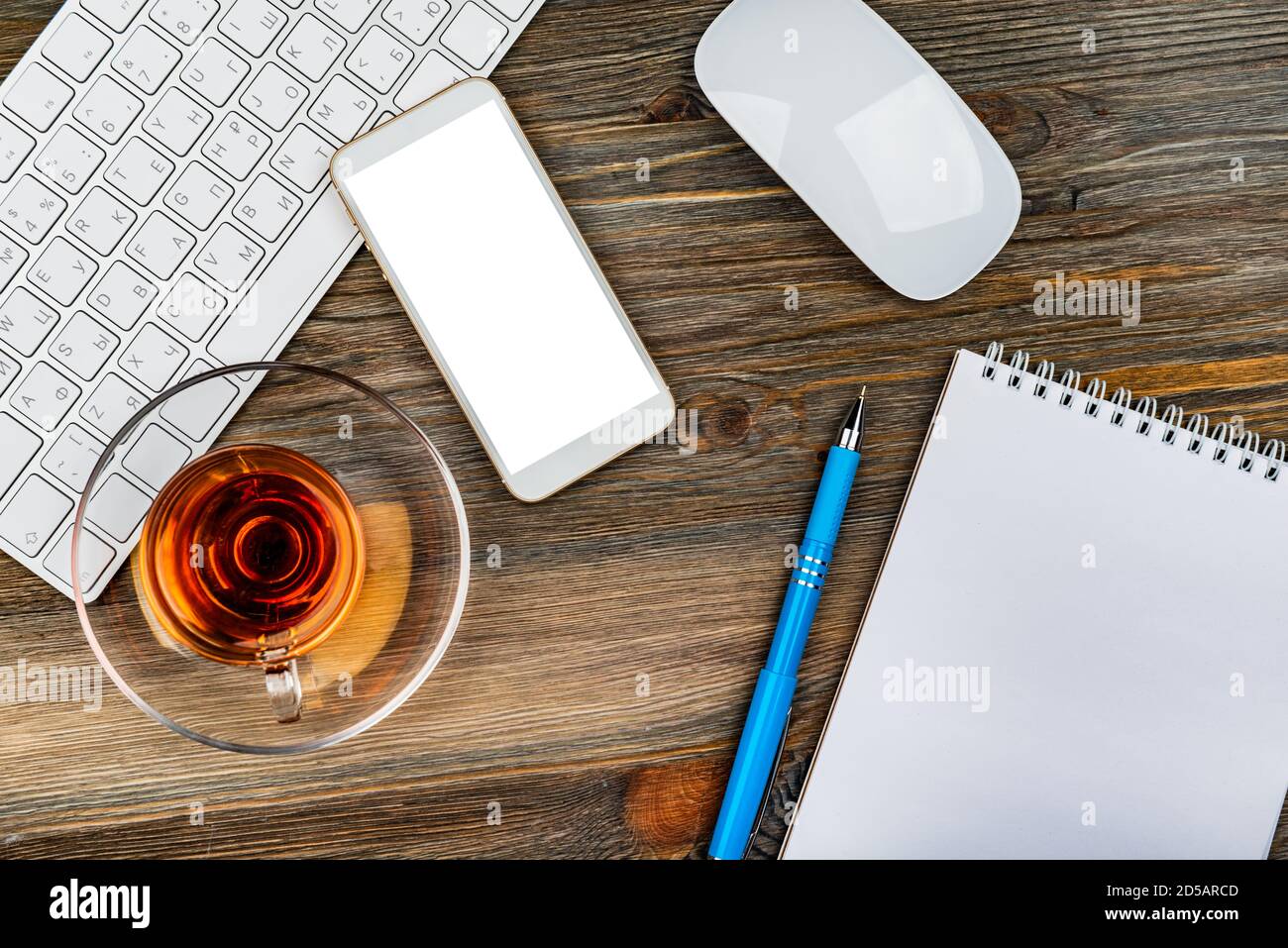 office table with computer keyboard, mouse, cup of tea and smartphone ...
