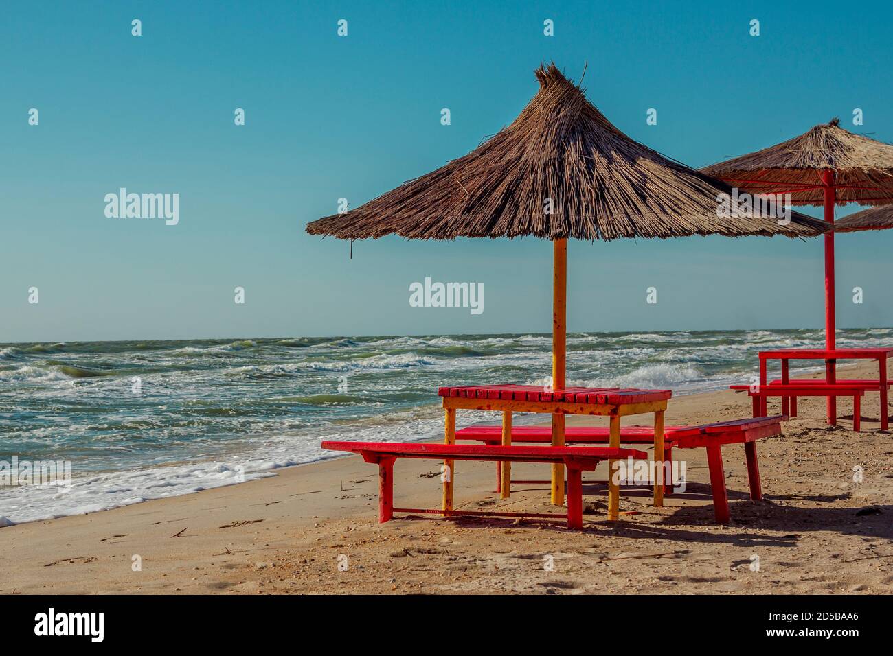 Summer landscape: table, benches and shade umbrella on the beach ...