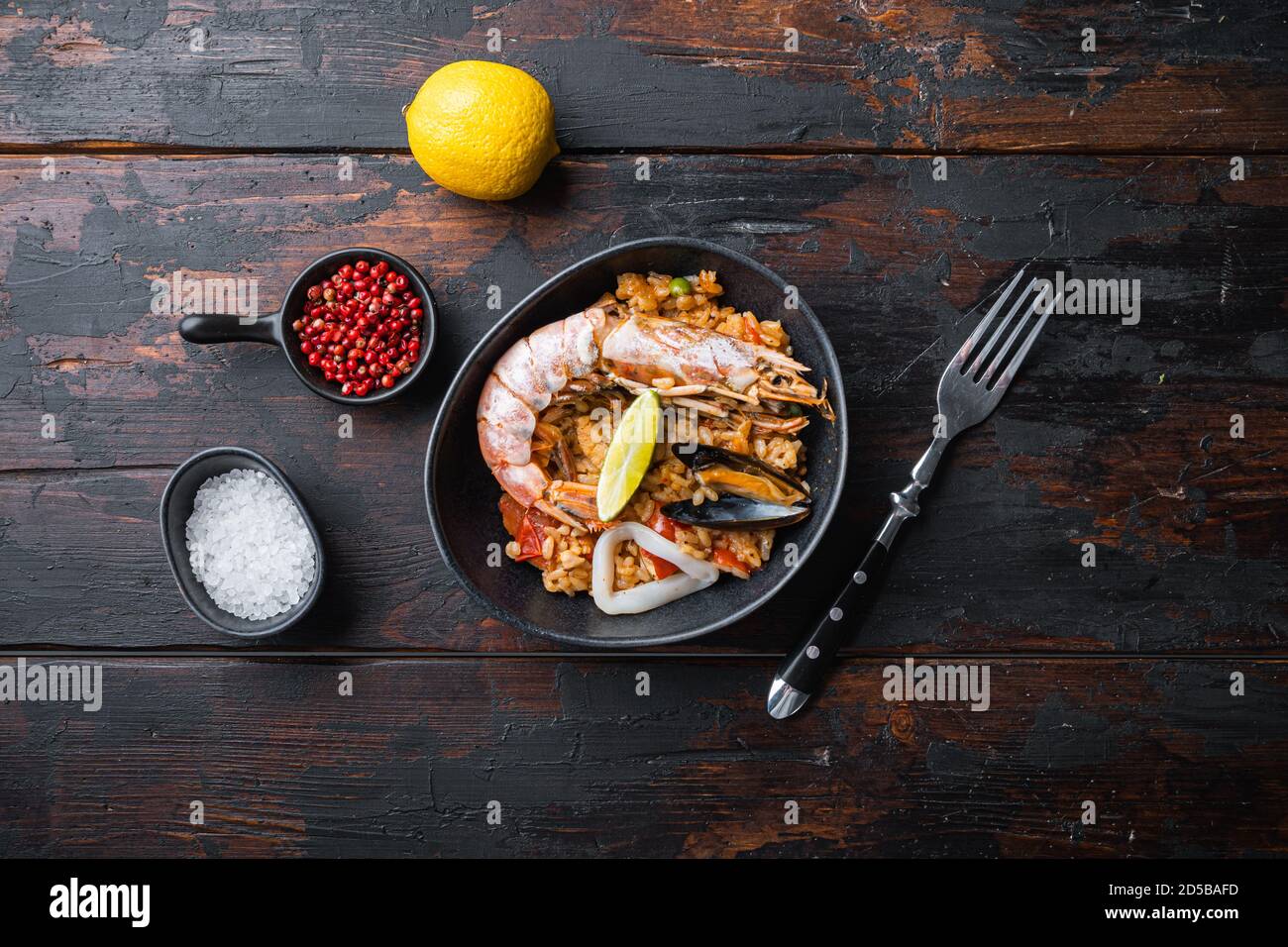 Traditional Spanish paella with seafood and chicken in black bowl on ...