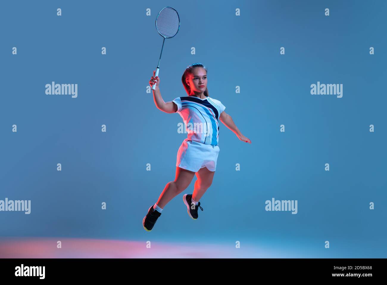 Action. Beautiful dwarf woman practicing in badminton isolated on blue ...