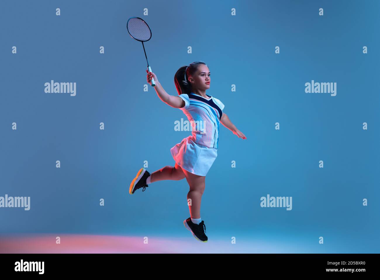 Action. Beautiful dwarf woman practicing in badminton isolated on blue ...
