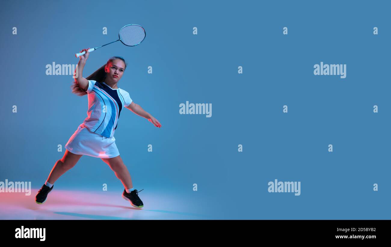 Motion. Beautiful dwarf woman practicing in badminton isolated on blue ...