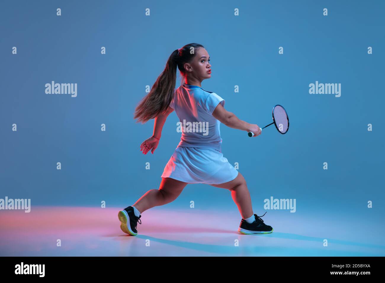 Motion. Beautiful dwarf woman practicing in badminton isolated on blue ...