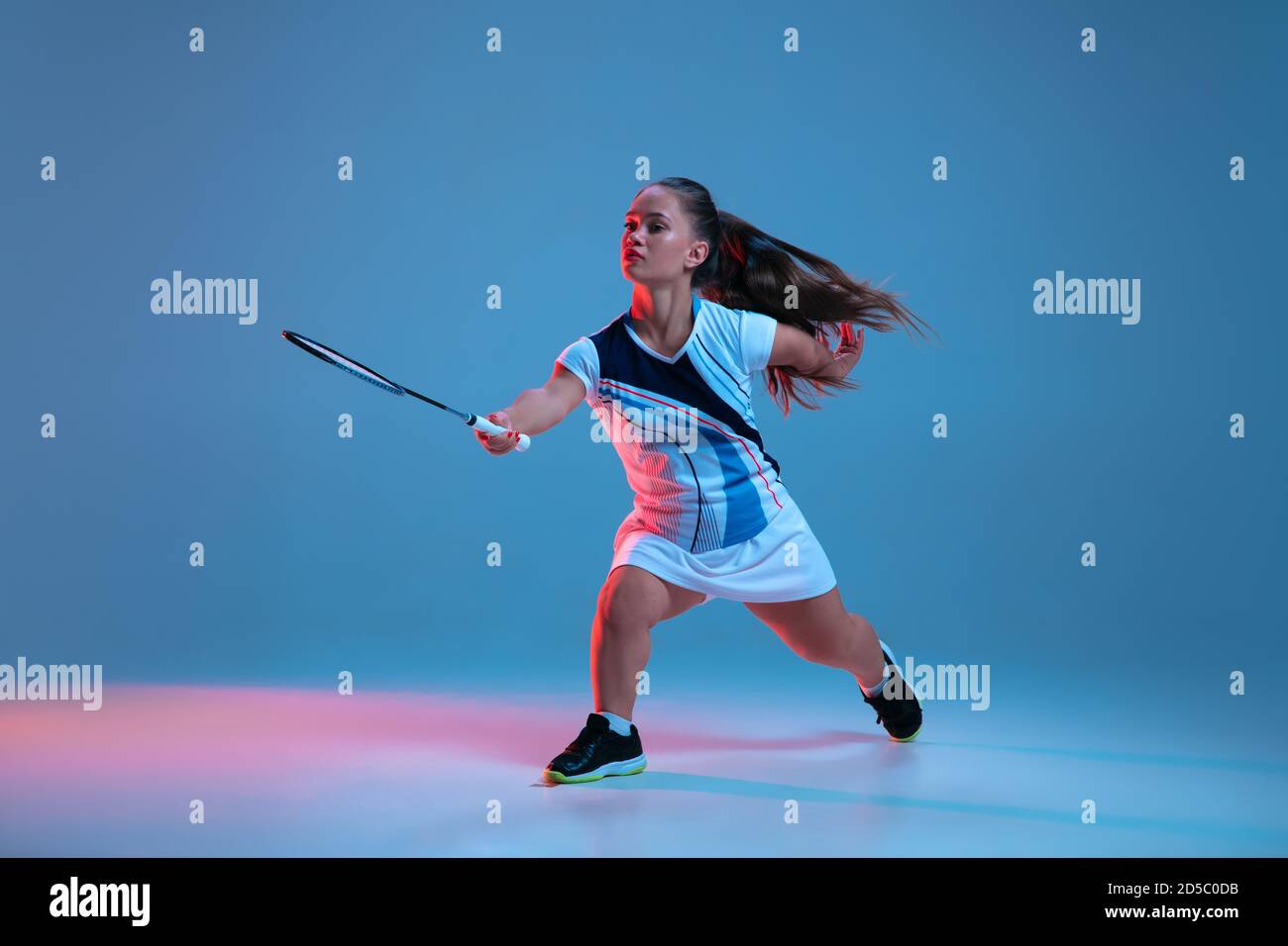 Motion. Beautiful dwarf woman practicing in badminton isolated on blue ...