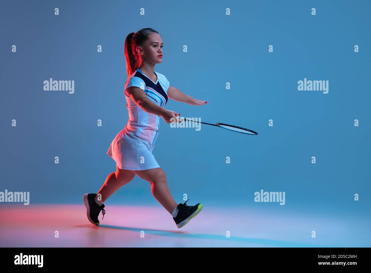 Motion. Beautiful dwarf woman practicing in badminton isolated on blue ...