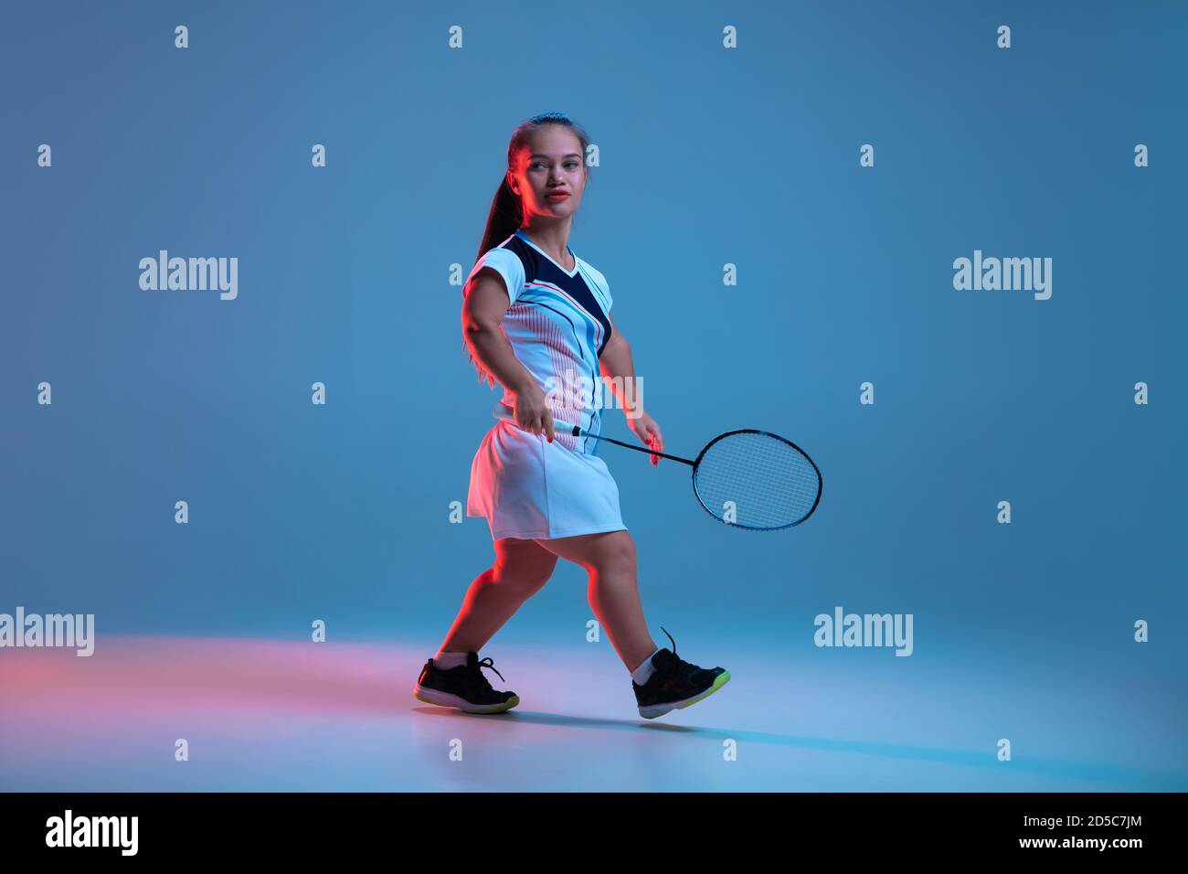 Winner. Beautiful dwarf woman practicing in badminton isolated on blue ...