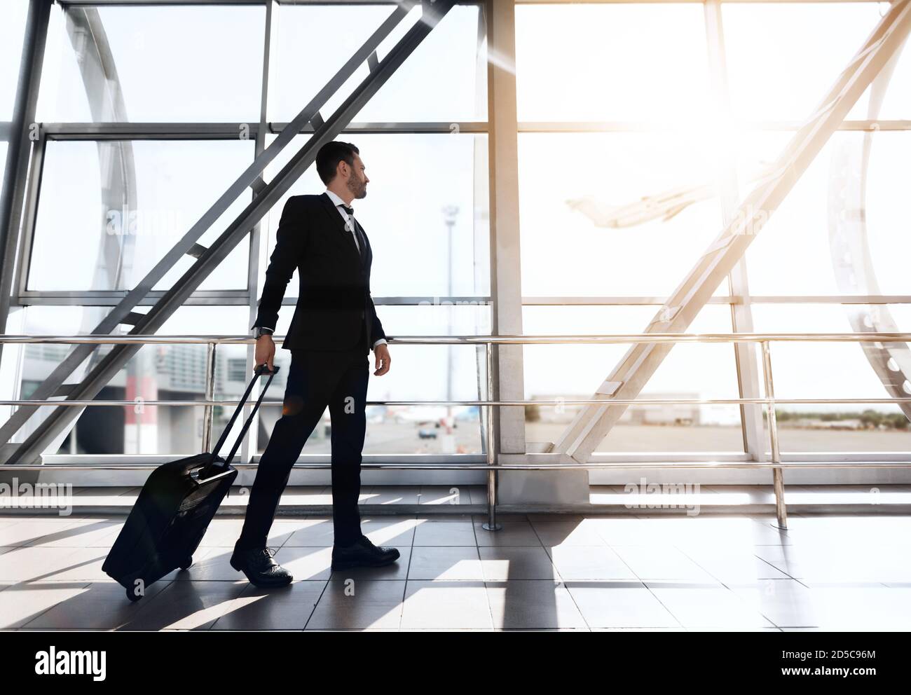 Businessman walking by airport terminal, looking through window Stock ... Businessman walking by airport terminal, looking through window Stock ...