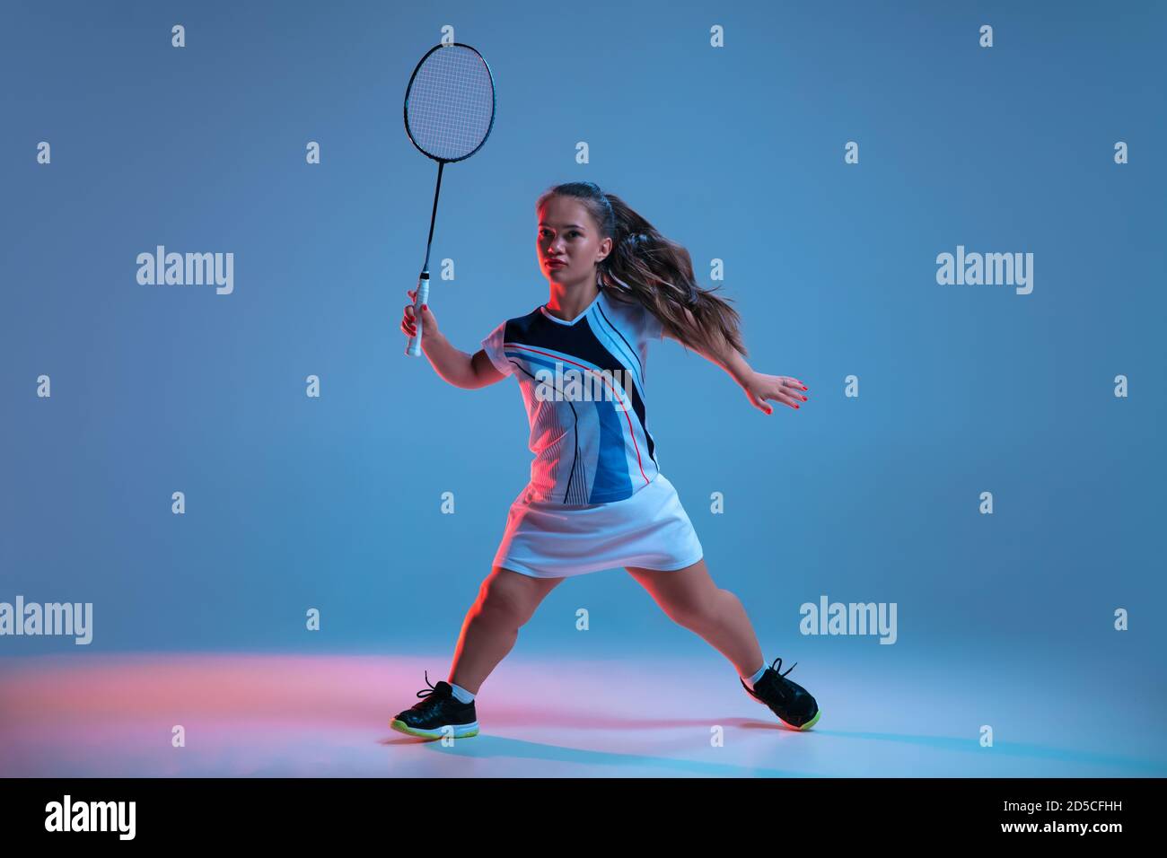 Energy. Beautiful dwarf woman practicing in badminton isolated on blue ...