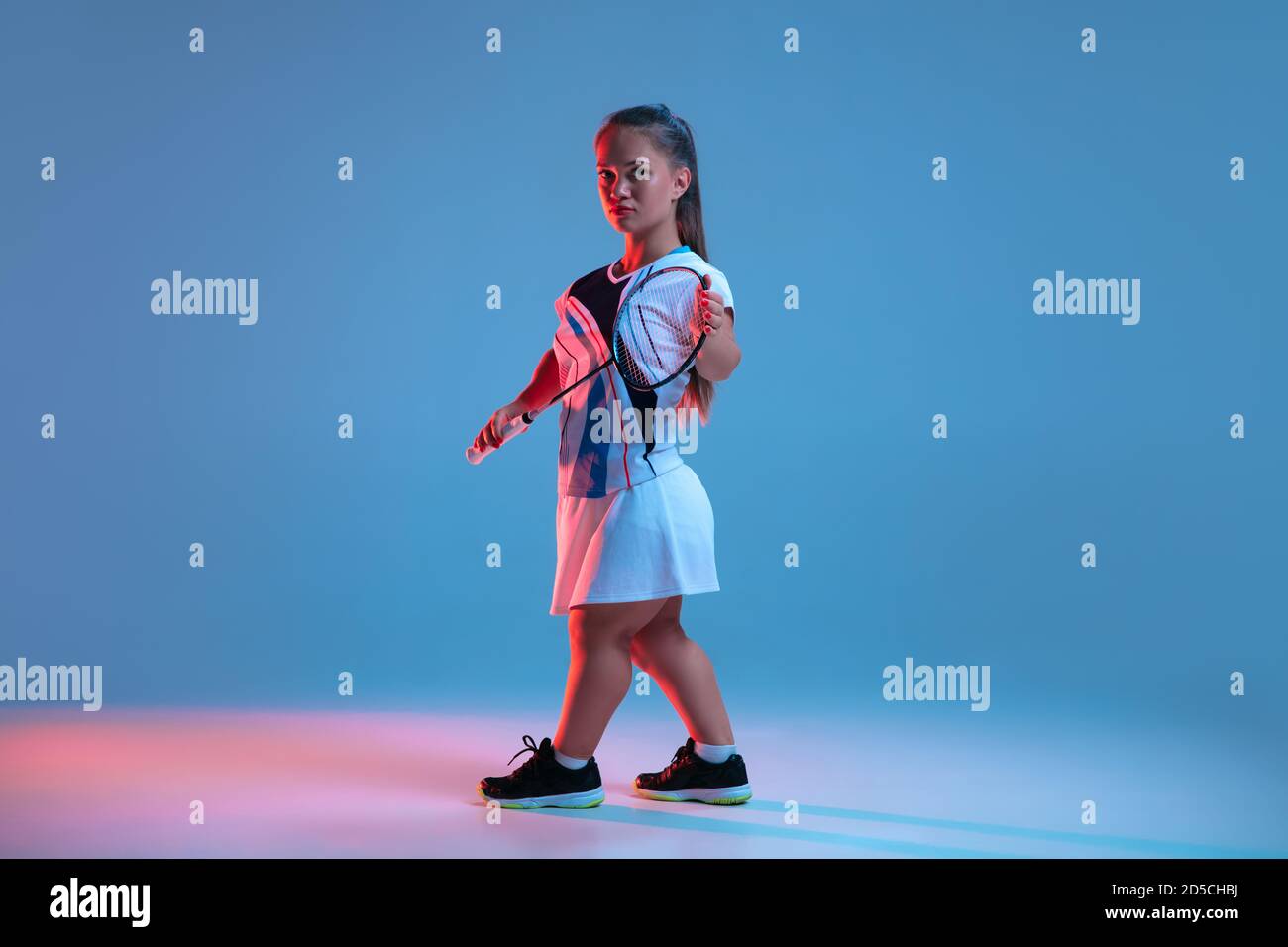 Energy. Beautiful dwarf woman practicing in badminton isolated on blue ...