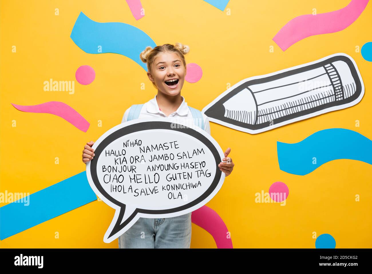 excited schoolchild holding speech bubble with greeting lettering near ...