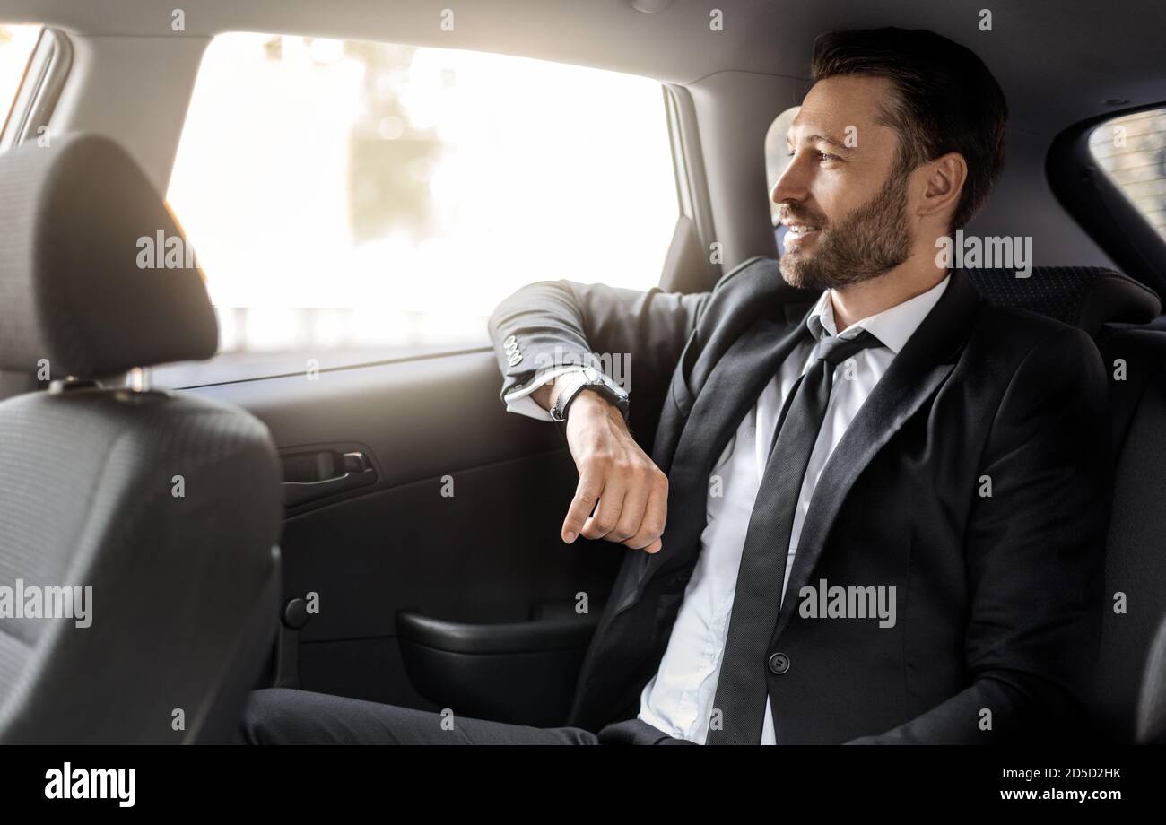 Successful businessman looking through window at car Stock Photo - Alamy